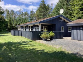 Um edifício de dois andares com fachada escura, antena parabólica e entrada com calçada de brita.