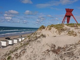 Uma praia com uma estrutura vermelha, edifícios brancos e o oceano.