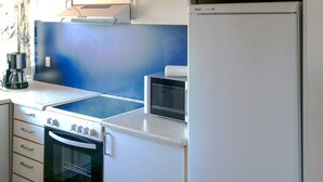 Uma cozinha equipada com fogão, forno, frigorífico e máquina de café.