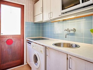 Cozinha compacta com máquina de lavar embutida, pia e micro-ondas.