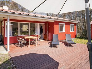 Uma cabana vermelha com deck de madeira, uma mesa e duas cadeiras.