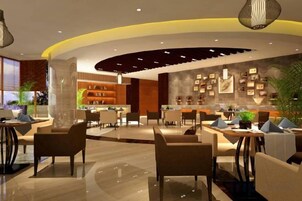 Um saguão de hotel moderno com um balcão de recepção curvo, área de estar e um bar.