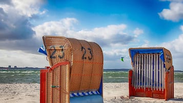 Duas cabanas de praia com os números 23 e 24, uma praia arenosa e o mar ao fundo.