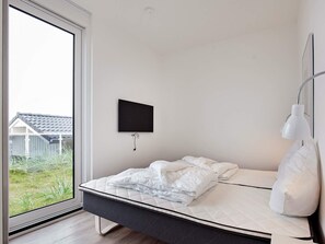Quarto com cama, televisão montada e abajur.