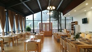 Um restaurante espaçoso com pé-direito alto, grandes janelas e diferentes opções de assentos.