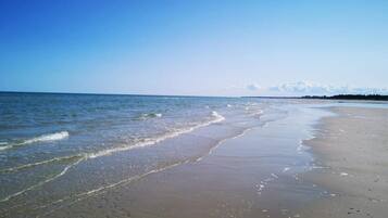 Uma praia com céu limpo e ondas suaves.