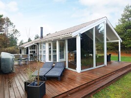 Uma casa moderna com varanda coberta, janelas amplas e um terraço.