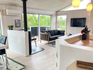 Uma sala de estar moderna com um sofá preto, uma mesa de centro de madeira e uma TV na parede.
