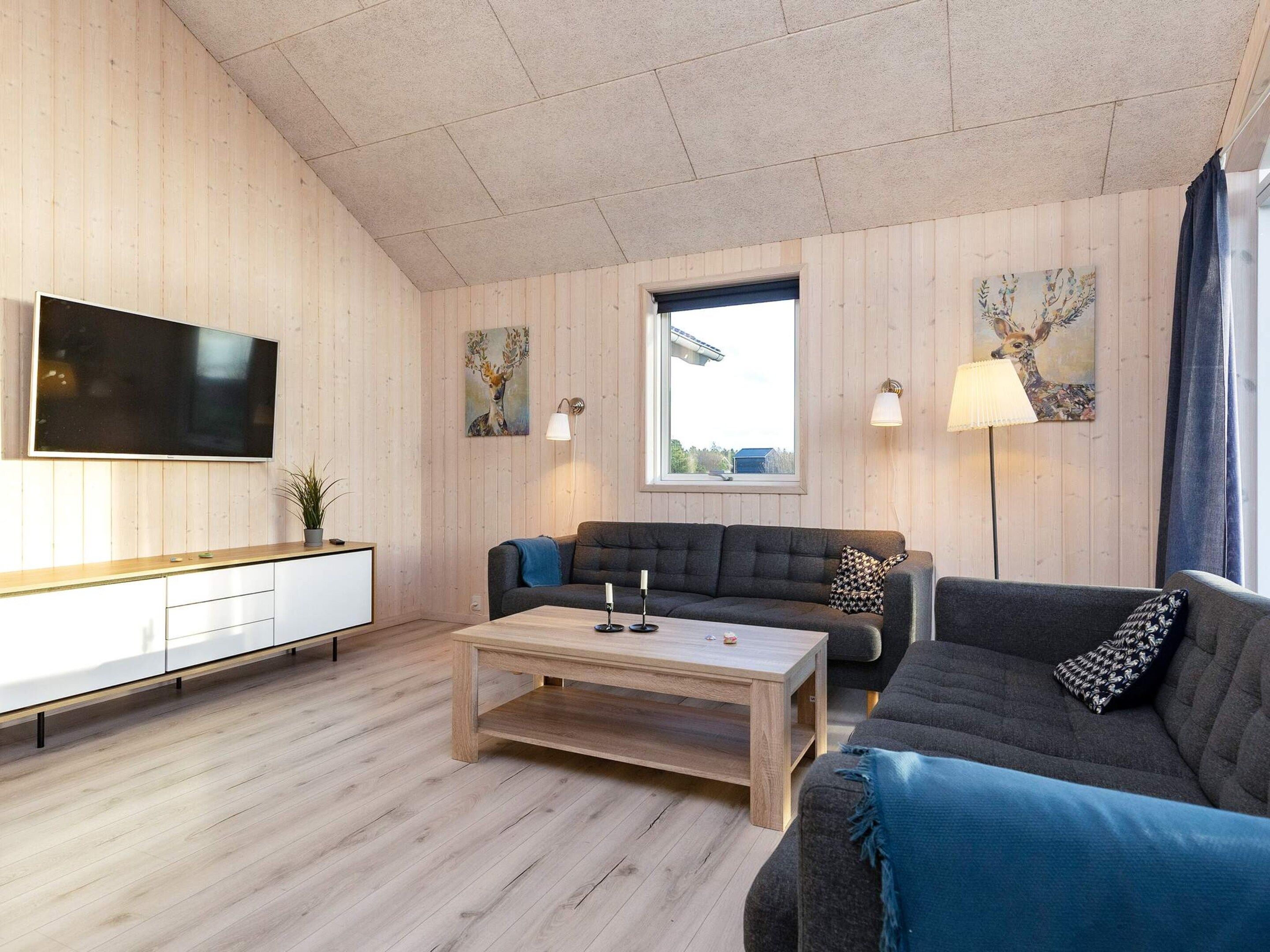 Uma sala de estar moderna com televisão de tela plana, sofá, mesa de centro e um armário.