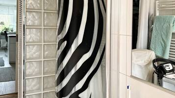 Casa de banho com espelho, porta-toalhas e cortina de chuveiro com padrão de zebra.