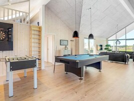 Um quarto espaçoso com mesa de bilhar, mesa de pebolim e mesa de sinuca.