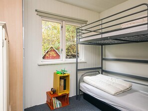 Quarto com beliche, janela, pequena estante e porta.