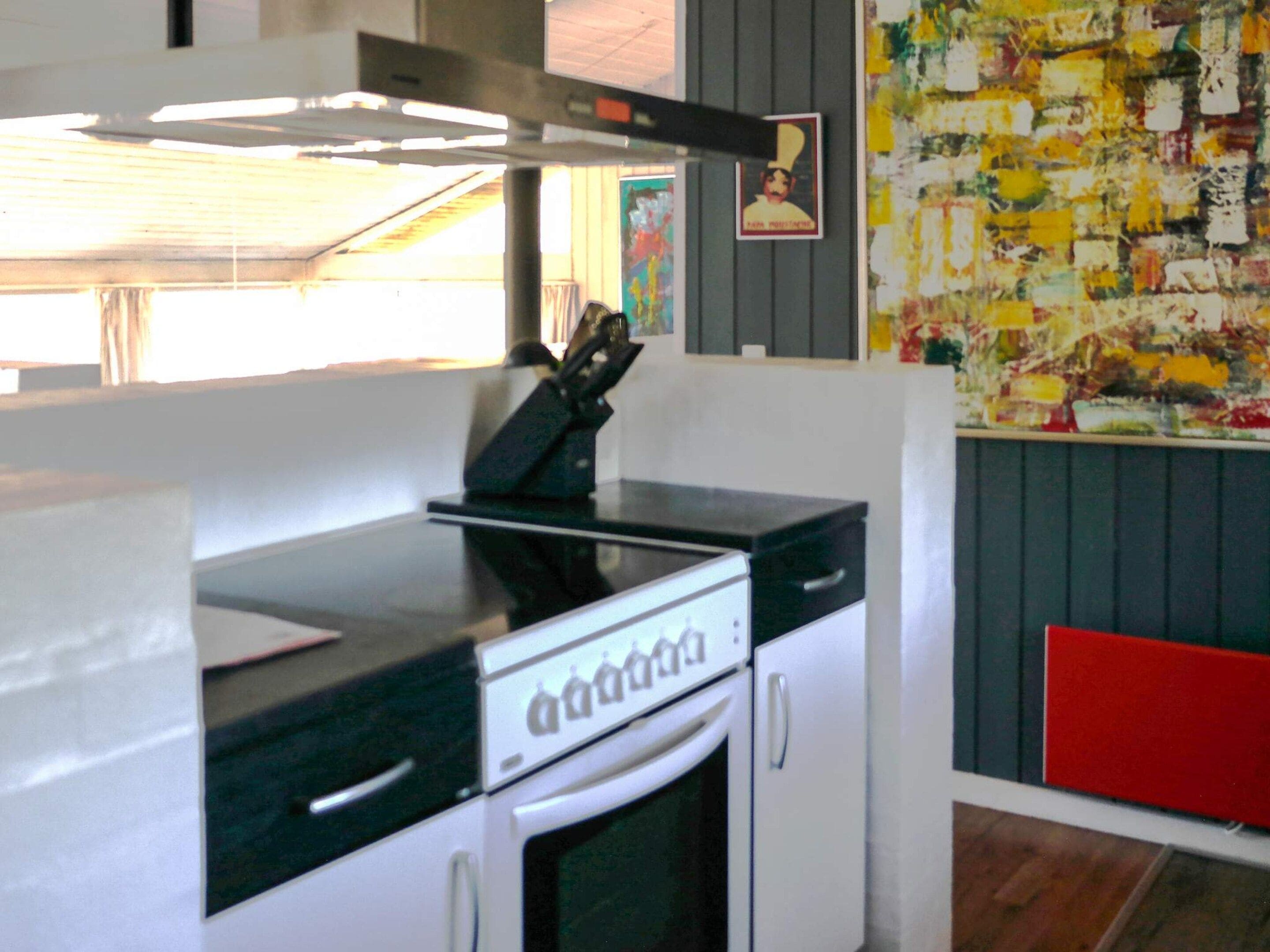 Uma cozinha com fogão, forno e uma faca sobre a bancada.