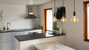 Cozinha moderna com ilha central, eletrodomésticos de aço inoxidável e iluminação pendente.