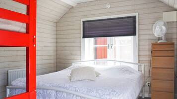 Quarto com beliche, janela com persianas, mesa de cabeceira com luminária e cômoda.