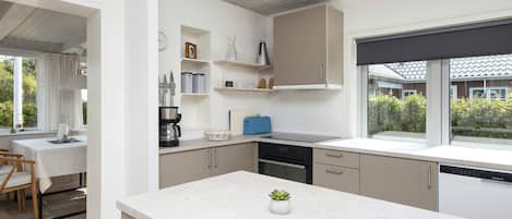 Cozinha moderna com ilha grande, eletrodomésticos embutidos e vista para o exterior.