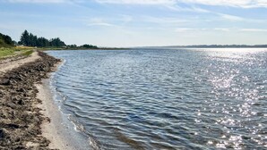 Uma praia com céu claro e águas calmas.