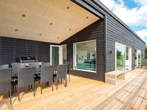 Uma casa moderna com um espaço de pátio que inclui um conjunto de jantar e uma churrasqueira.