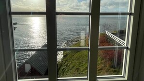 Uma janela com vista para o mar e uma costa distante.