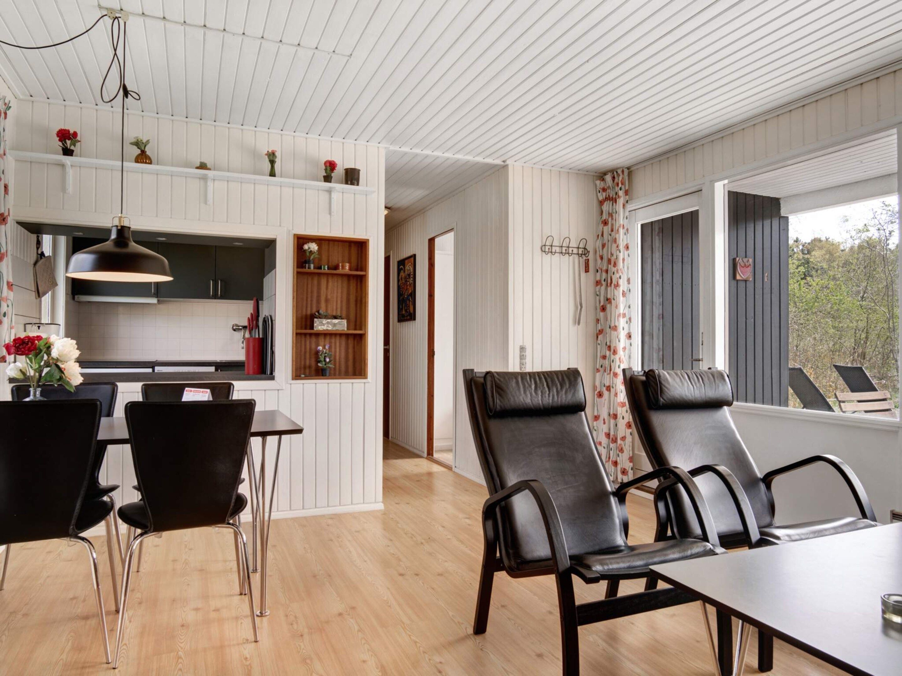 Interior moderno com área de jantar, cozinha e varanda com cadeiras.