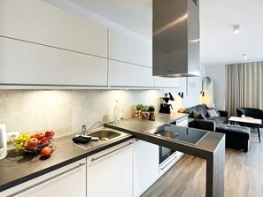 Cozinha moderna com forno embutido, pia e bancada com uma fruteira.