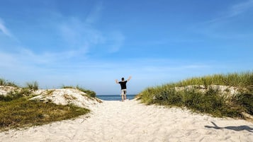 Uma trilha que leva à praia, com dunas de ambos os lados.