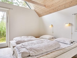 Quarto com duas camas, uma claraboia e luminárias fixadas na parede.