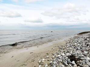 Uma praia rochosa com águas calmas e céu nublado.