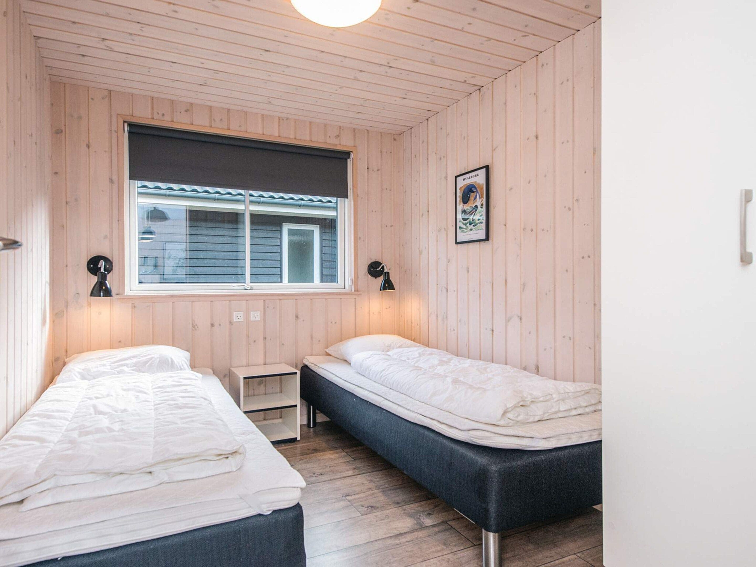 Quarto com duas camas, uma janela e uma mesinha.