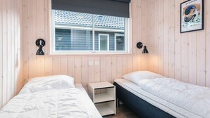 Quarto com duas camas, janela com vista para um edifício e um quadro na parede.