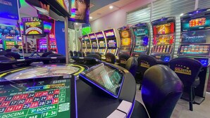 Um cassino com máquinas caça-níqueis, mesas de roleta e mesas de blackjack.