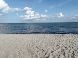 Uma praia com céu claro e mar calmo.