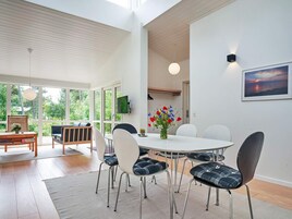 Uma área de refeições moderna com mesa redonda, cadeiras brancas e um vaso de flores.