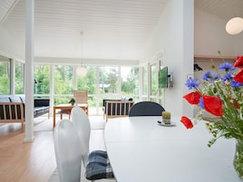 Uma área de refeições moderna com uma mesa branca, cadeiras e um vaso de flores.