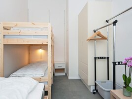 Uma cama de beliche com uma pequena mesa de cabeceira e um cabideiro.