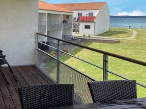 Varanda com mobiliário de vime com vista para uma área gramada e um edifício com telhado vermelho.