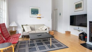 Uma sala de estar moderna com sofá, poltronas vermelhas, mesa de centro, televisão e lareira.