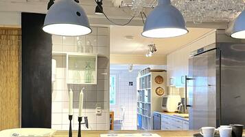 Uma cozinha moderna com iluminação pendente, geladeira e bancada com uma balança e xícaras.
