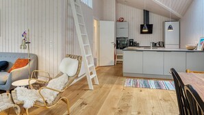 Um loft espaçoso com pé direito alto, cama no mezanino, cozinha com uma ilha grande e área de refeições.