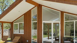 Uma casa moderna com deck de madeira, grandes portas de vidro deslizantes e móveis para área externa.