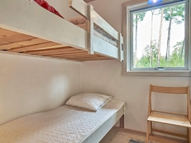 Uma cama de solteiro, uma cama beliche e uma cadeira.