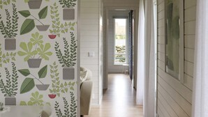 Um corredor com área de jantar, com mesa e cadeiras, um sofá e vista para o exterior através de uma porta.