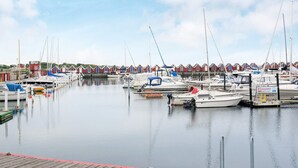 Marina com barcos atracados, fileira de edifícios vermelhos e azuis, e céu claro.