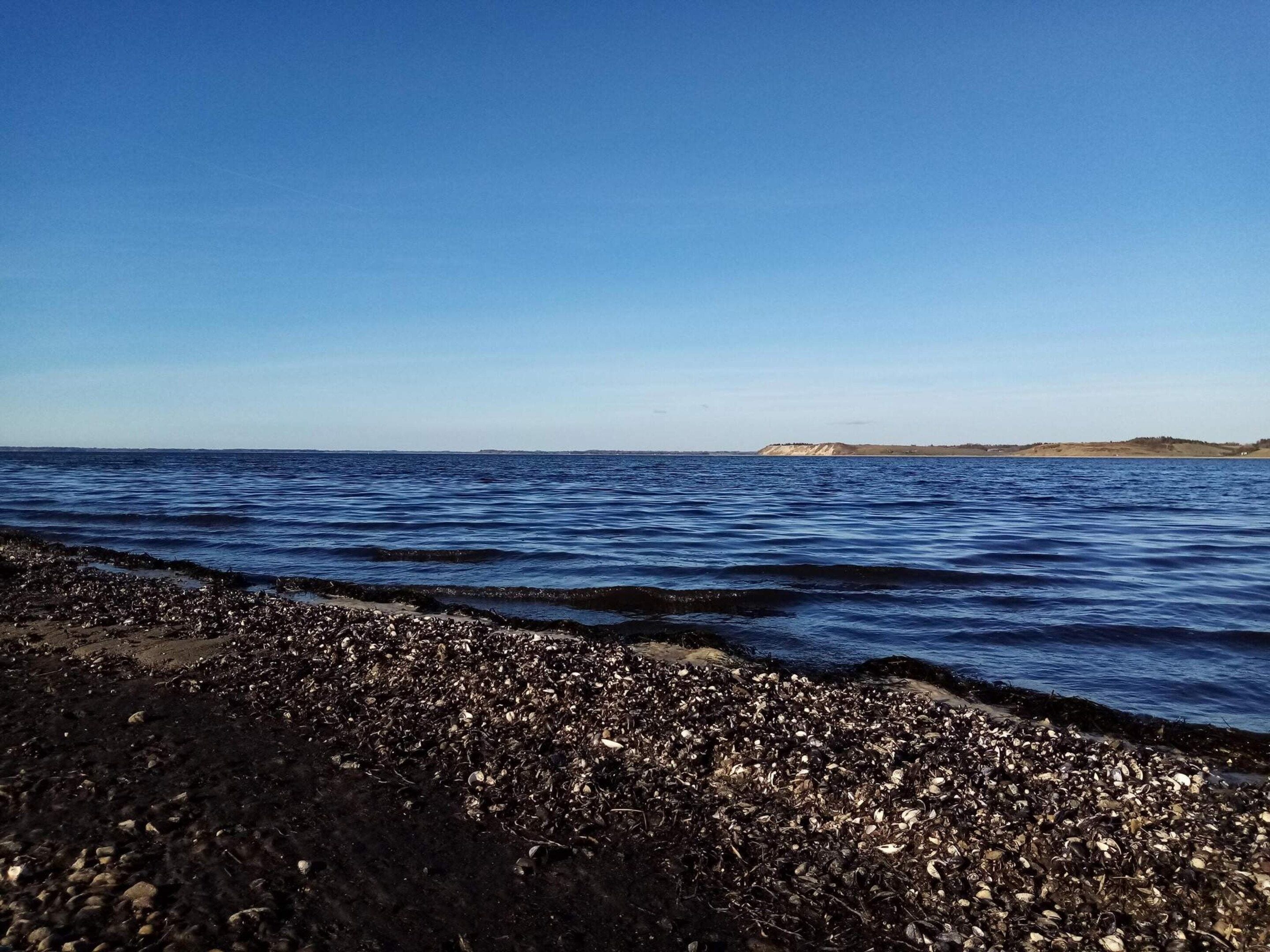 Uma praia com costa rochosa e mar calmo.