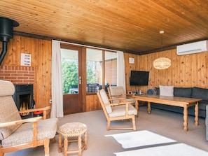 Um quarto aconchegante com lareira, móveis de madeira, televisão e uma janela grande.
