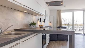 Cozinha moderna com ilha central, eletrodomésticos de aço inoxidável e vista para a marina através de amplas janelas.