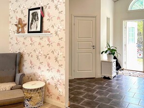 Sala de estar com sofá, mesa redonda e prateleira fixada na parede, exibindo uma moldura com imagem e objetos decorativos.
