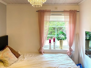 Quarto com cama, janela com cortinas, um lustre e ar-condicionado fixado na parede.