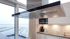 Cozinha moderna com exaustor de aço inoxidável, micro-ondas embutido e uma grande janela com vista para uma ponte.