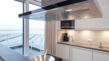 Cozinha moderna com exaustor de aço inoxidável, micro-ondas embutido e uma grande janela com vista para uma ponte.